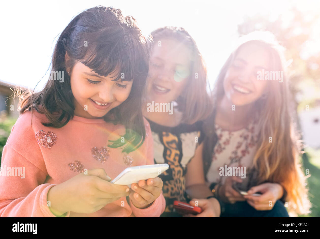 Three happy girls using their smartphones outdoors Stock Photo - Alamy