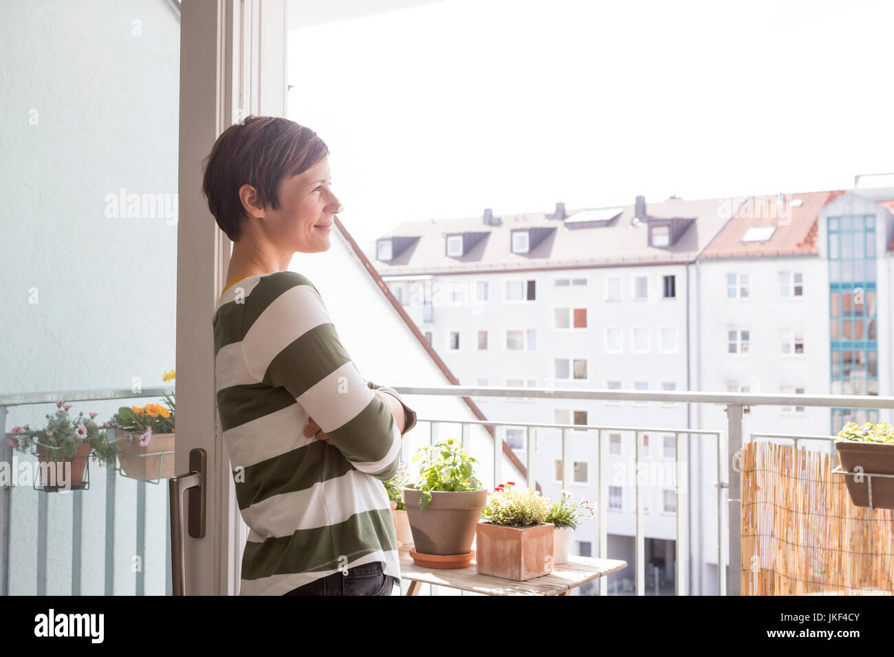 Smiling woman standing on balcony looking at distance Stock Photo - Alamy
