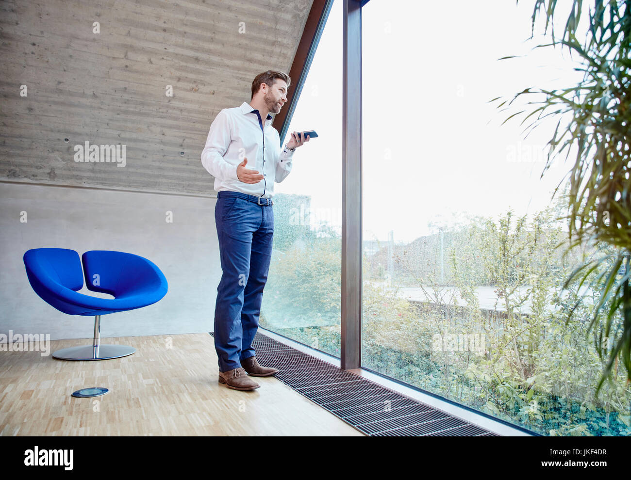 Businessman using cell phone in attic office at the window Stock Photo ...