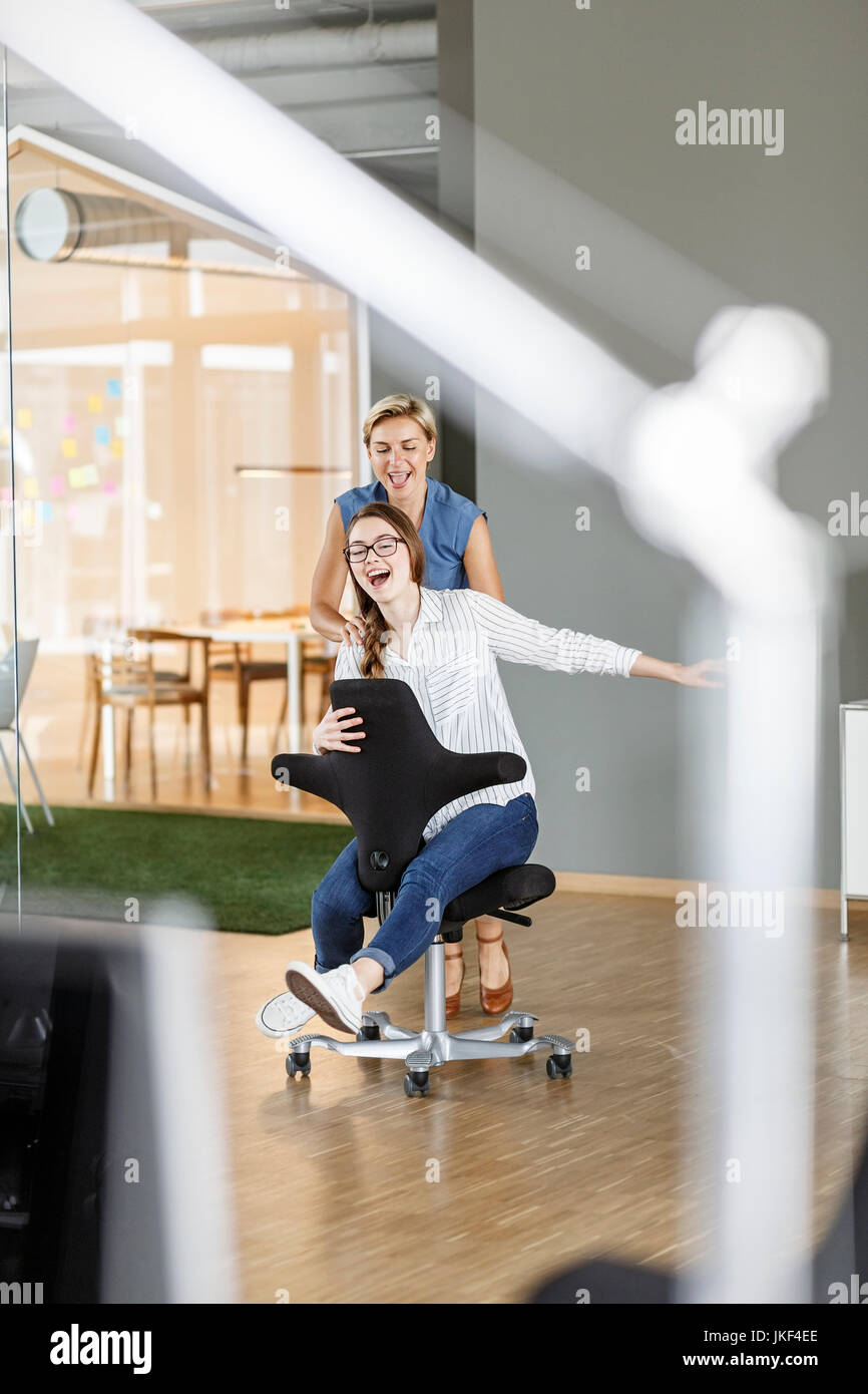 Playful employee pushing colleague on office chair Stock Photo - Alamy