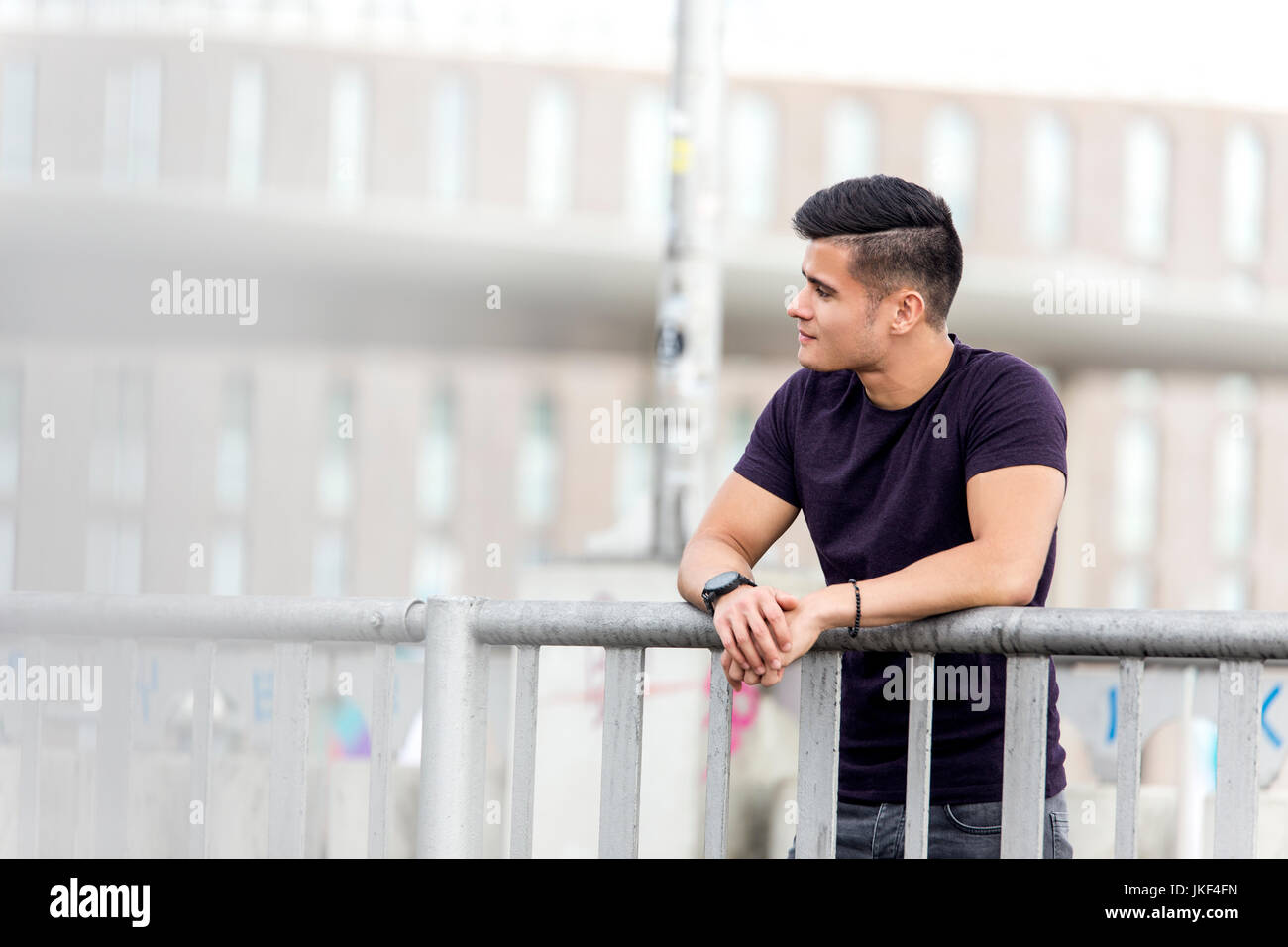 Young man leaning on railing looking away Stock Photo - Alamy