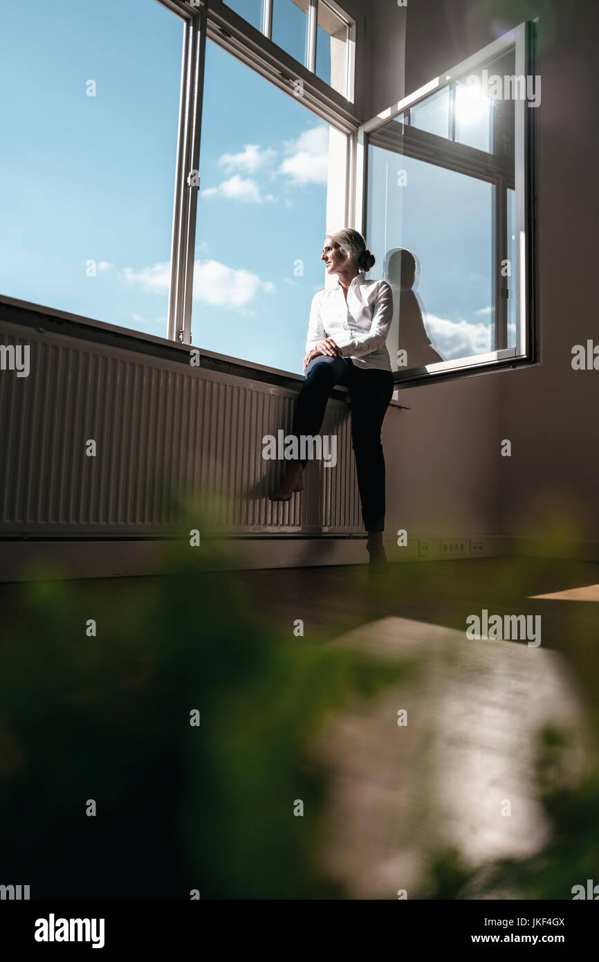 Businesswoman in office looking out of window Stock Photo - Alamy
