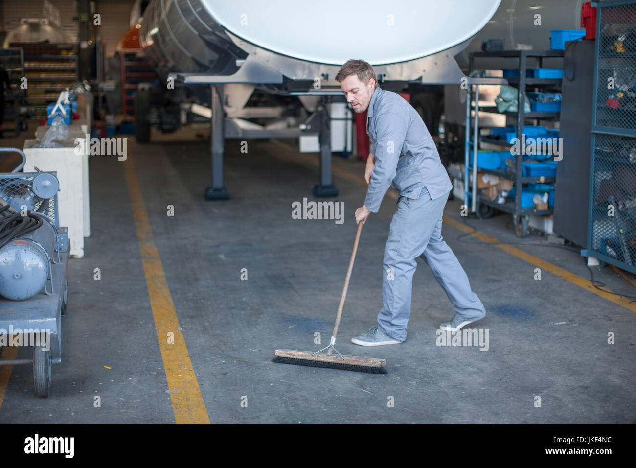 Industrial worker sweeping floor Stock Photo - Alamy