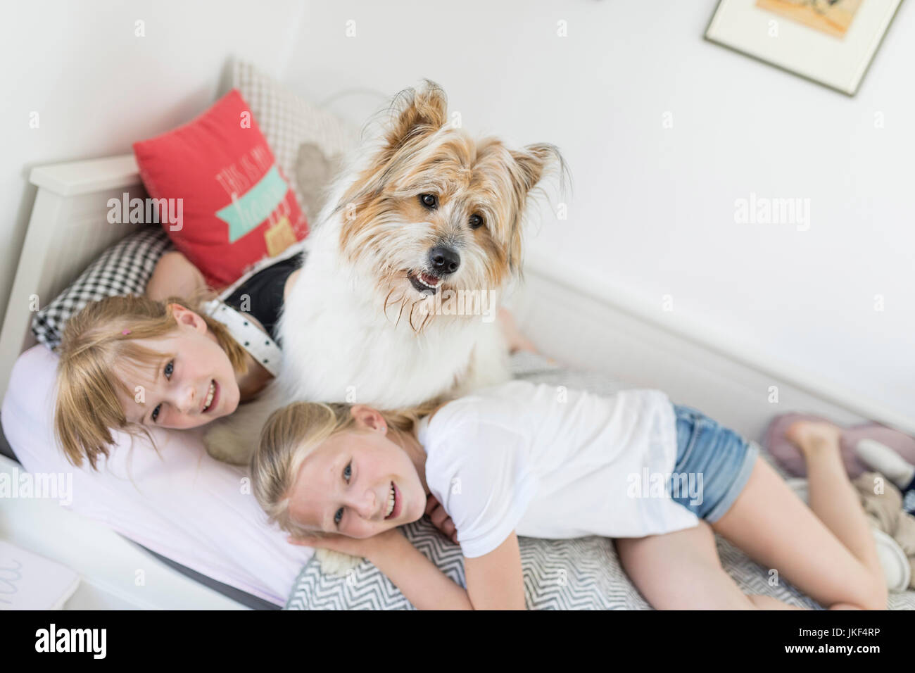 Two sisters cuddling with dog in bed Stock Photo - Alamy