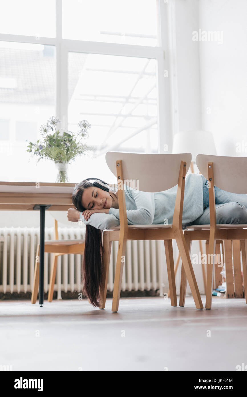 Young woman sleeping on chairs wearing headphones Stock Photo - Alamy