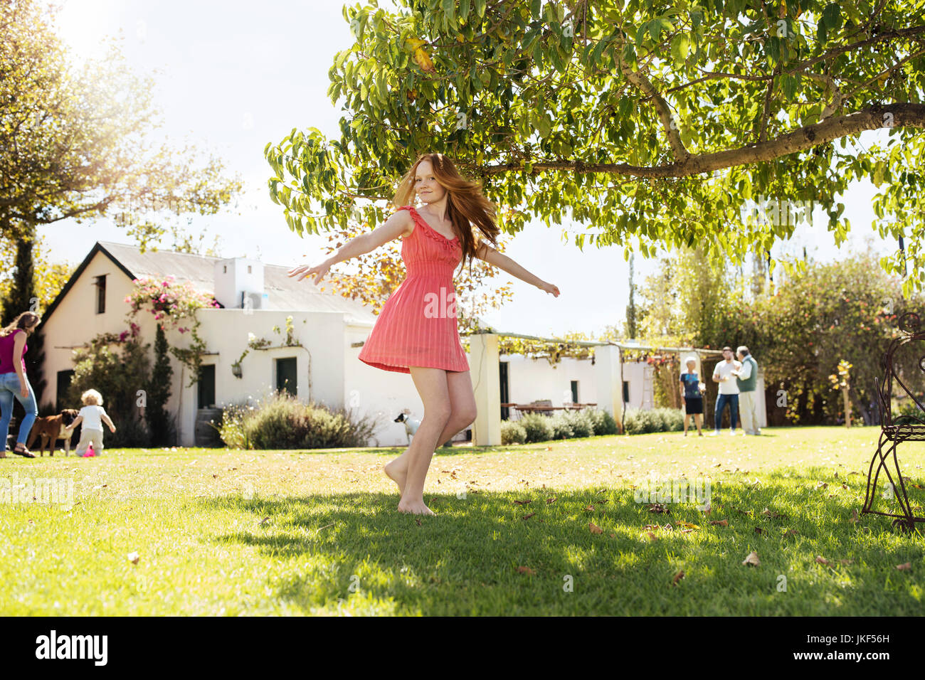 Girl wearing a red dress spinning around outside on the lawn Stock ...