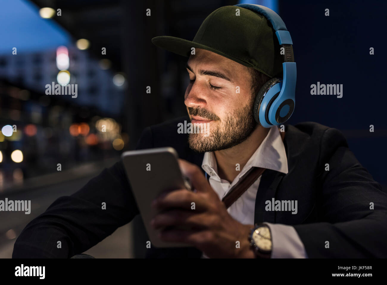 Young man in the city with headphones and cell phone in the evening ...