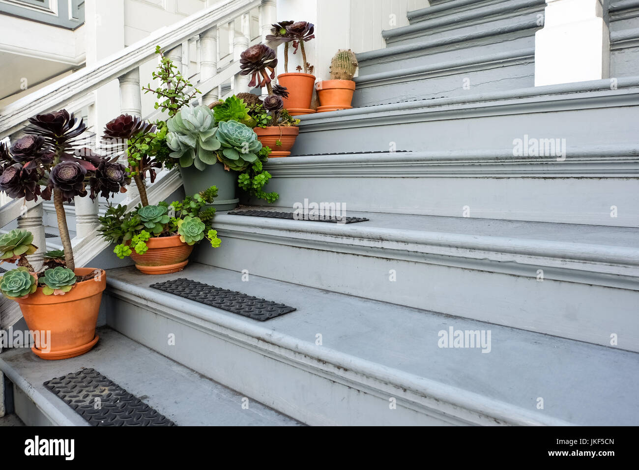 Flowers in pot on the wooden steps of a house entrance Stock Photo - Alamy