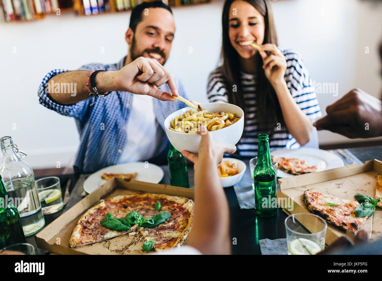 Happy friends having French fries and pizza at home Stock Photo - Alamy