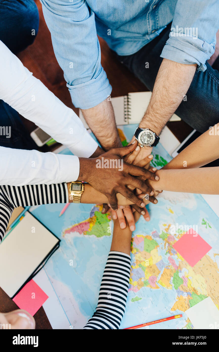 Group of friends stacking hands above world map Stock Photo - Alamy