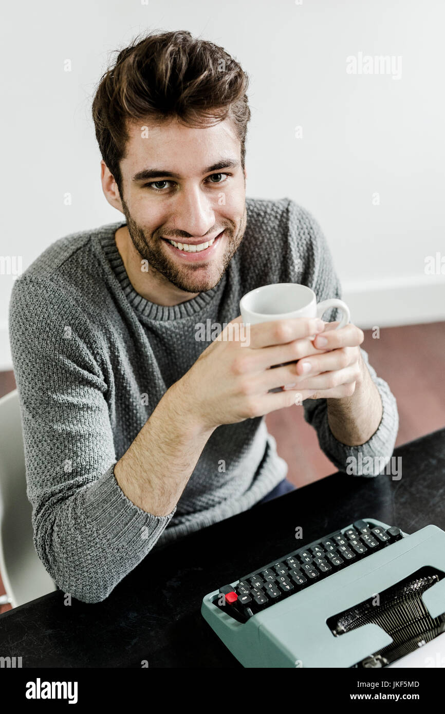 Portrait of smiling young man with typewriter Stock Photo - Alamy