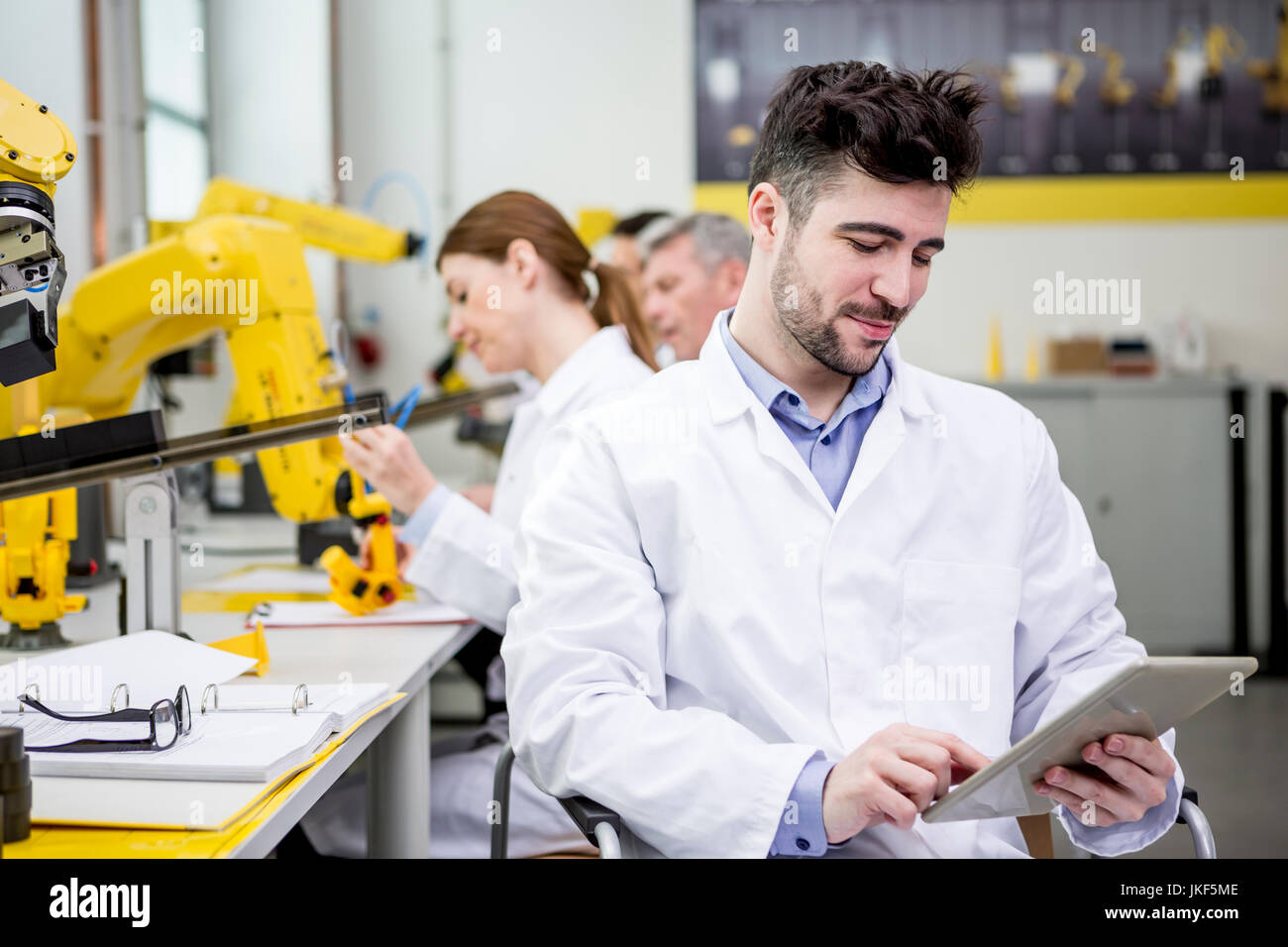 Engineer holding tablet with industrial robots in background Stock ...
