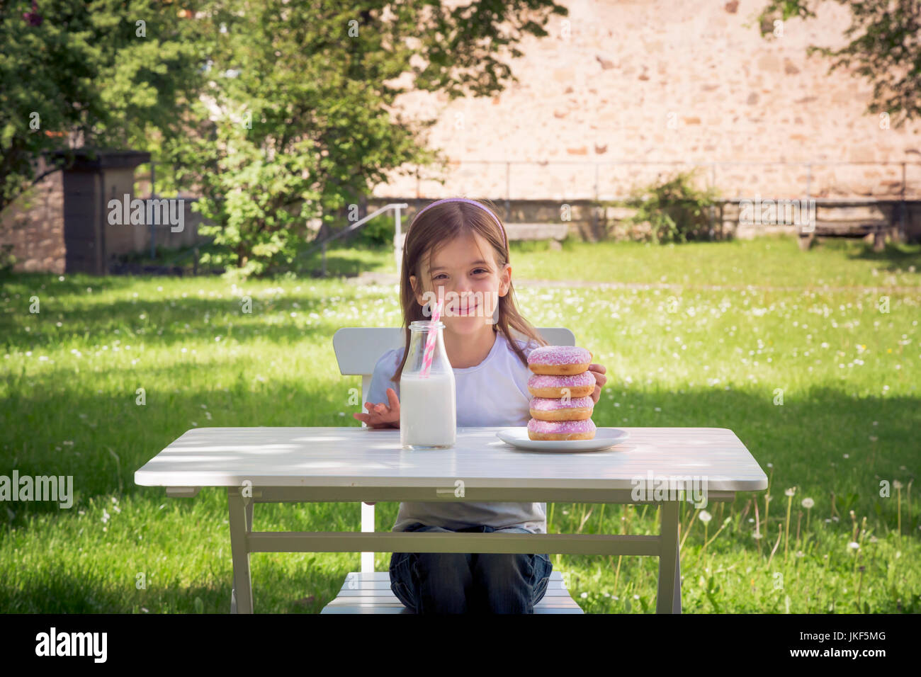 Girl with stack of donuts on garden table Stock Photo - Alamy