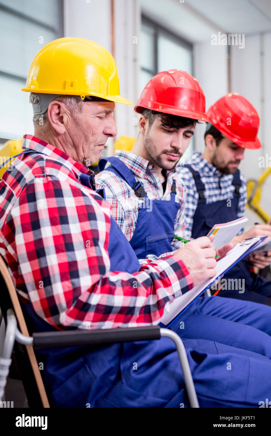 Colleagues wearing hard hats checking document Stock Photo - Alamy