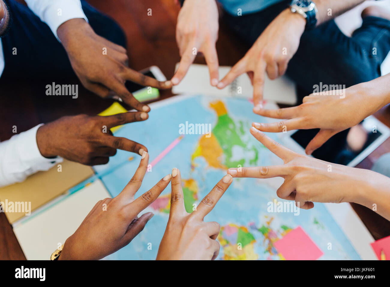 Group of friends making hand sign above world map Stock Photo - Alamy