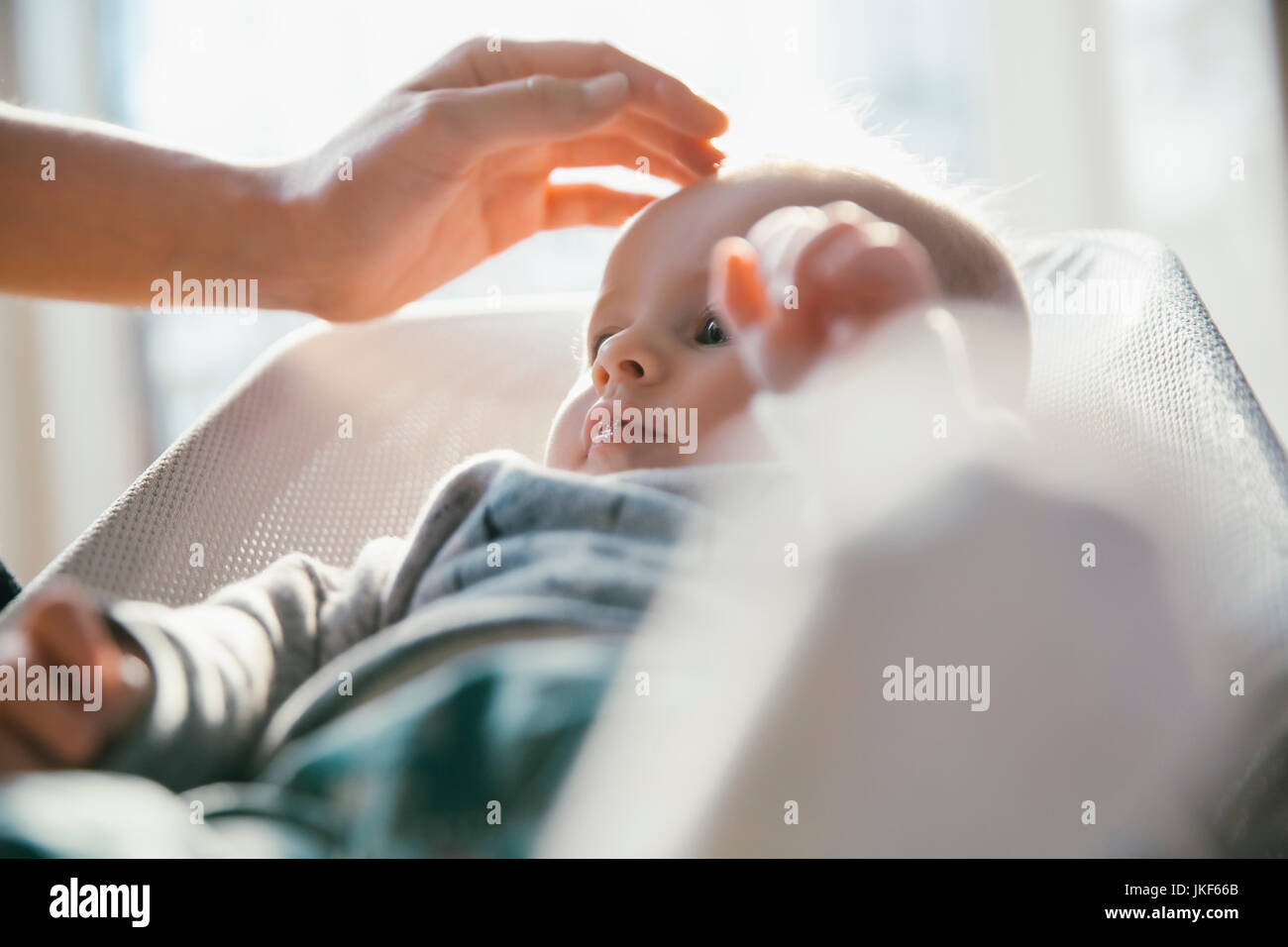 Woman's hand touching baby's forehead Stock Photo - Alamy