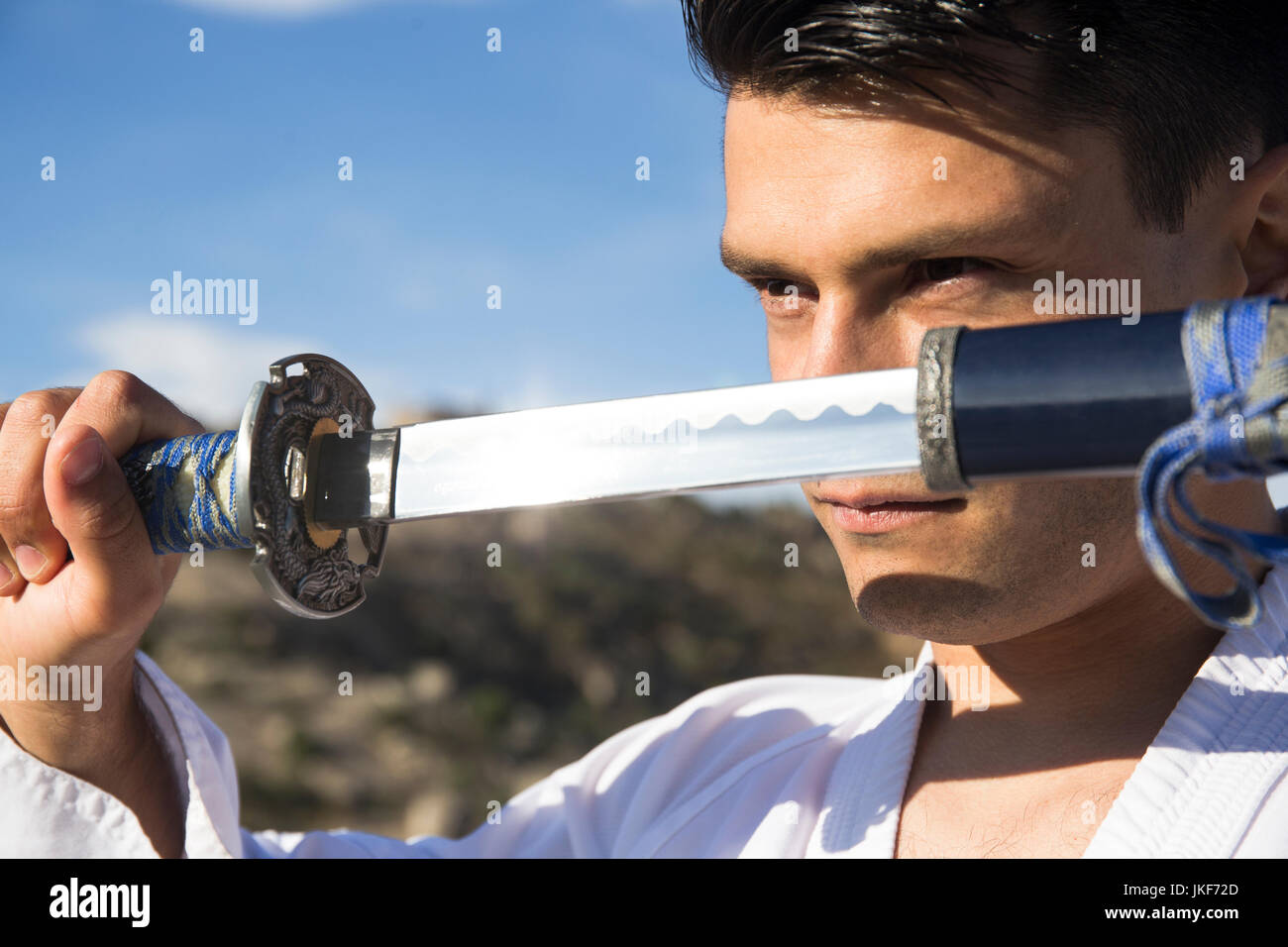 Man with defiant eyes drawing his katana sword Stock Photo - Alamy