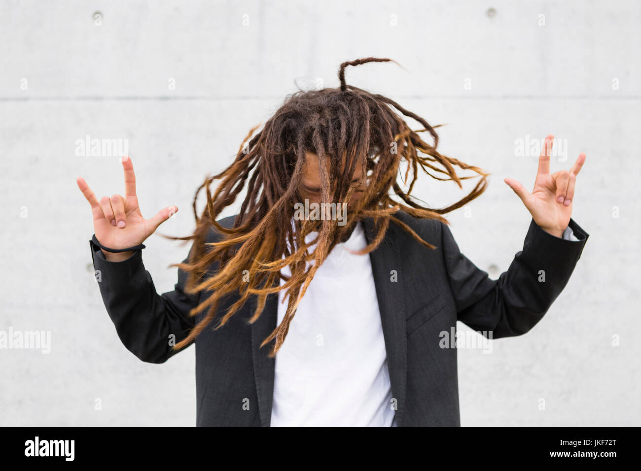 Young businessman tossing his dreadlocks showing Rock And Roll Sign ...