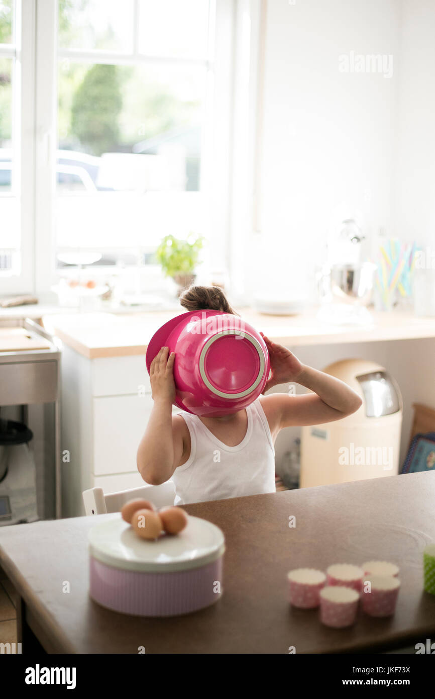 Little girl in kitchen covering her face with pink mixing bowl Stock ...