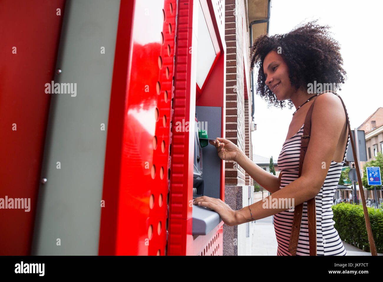 Smiling woman pushing credit card at cash dispenser Stock Photo - Alamy