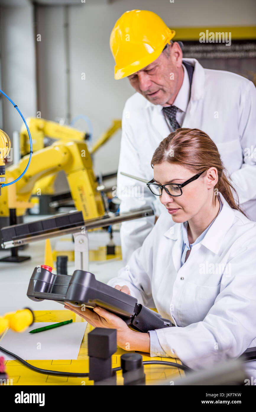 Two engineers in factory looking at device Stock Photo - Alamy