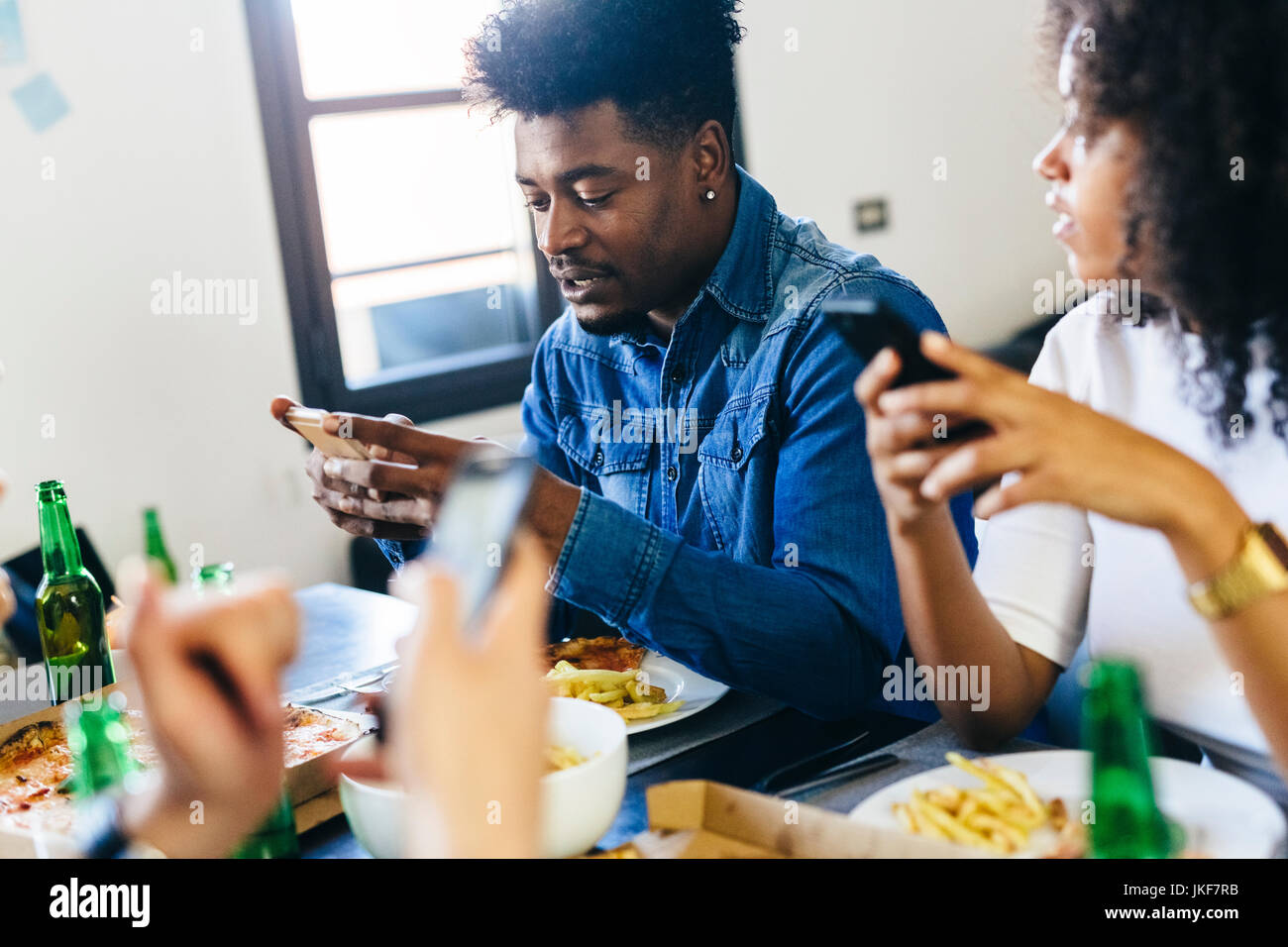 Friends using cell phones at dining table Stock Photo - Alamy