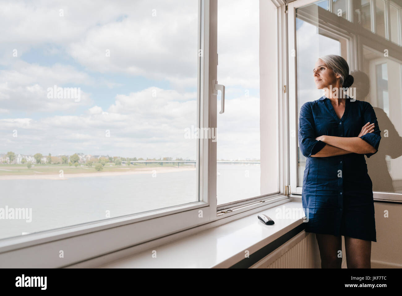 Businesswoman looking out of window in waterfront office Stock Photo ...