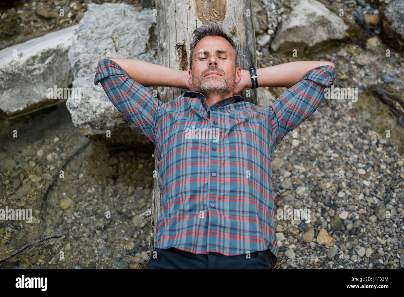 Hiker having a break lying on a log Stock Photo - Alamy