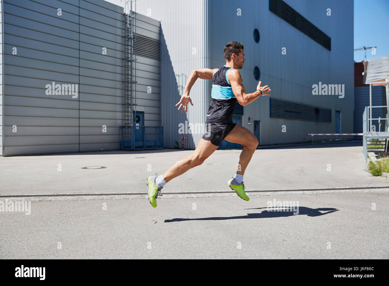 Fit man running along building Stock Photo - Alamy
