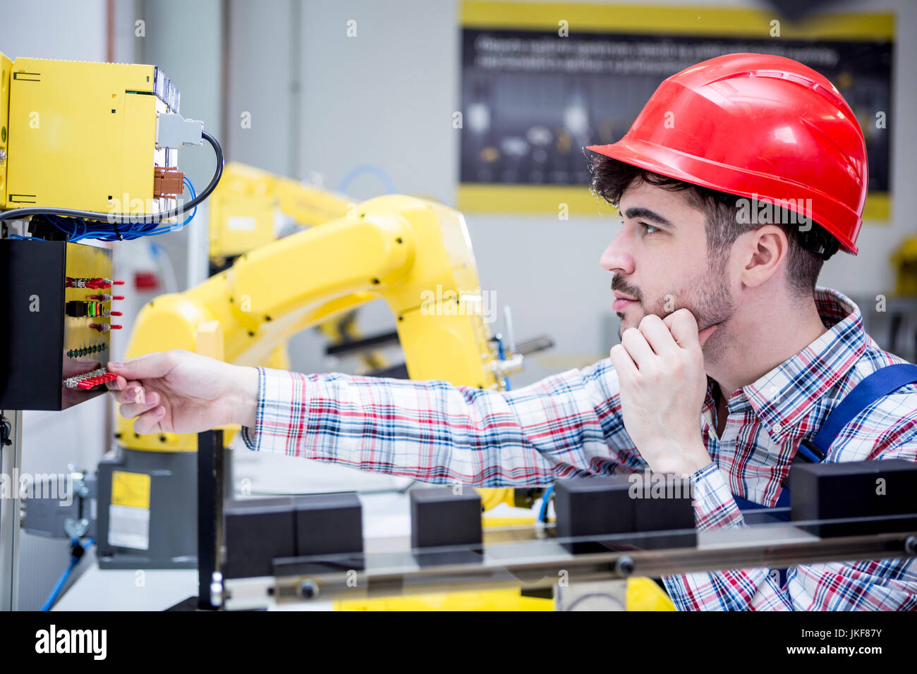 Man wearing hard hat adjusting industrial robot Stock Photo - Alamy