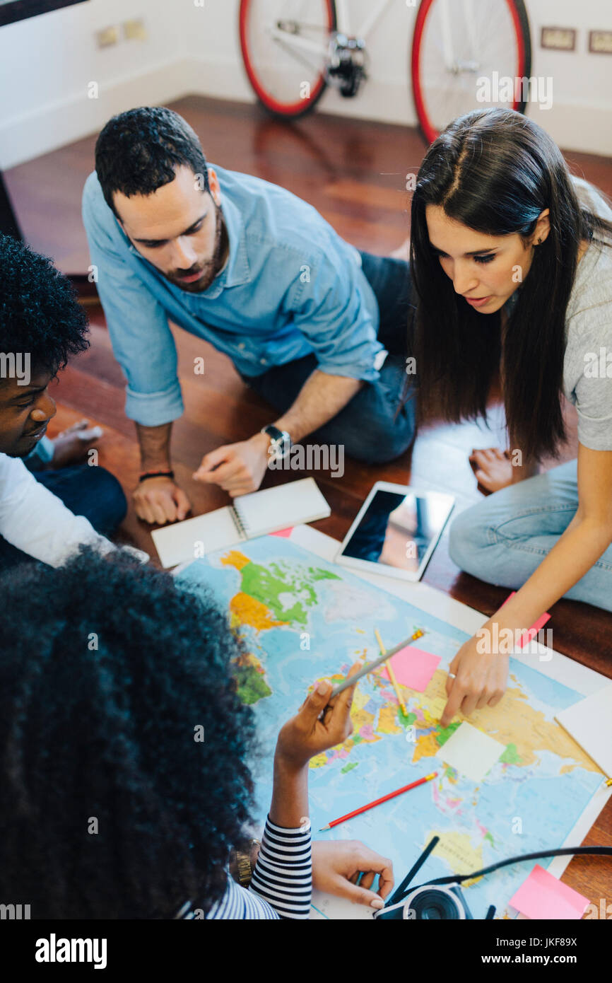 Group of friends looking at a world map Stock Photo - Alamy