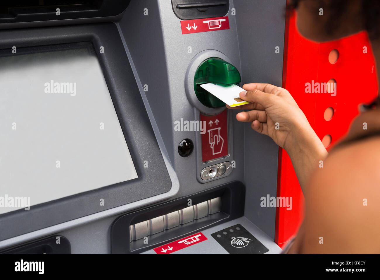 Woman pushing credit card at cash dispenser, partial view Stock Photo ...