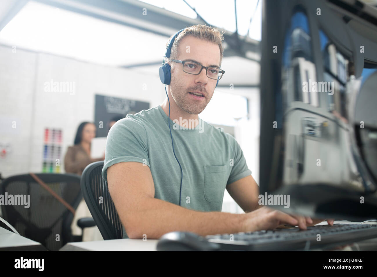 Employee wearing headphones at desk Stock Photo - Alamy