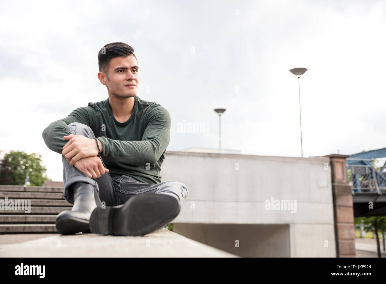 Young man sitting on wall in the city Stock Photo - Alamy