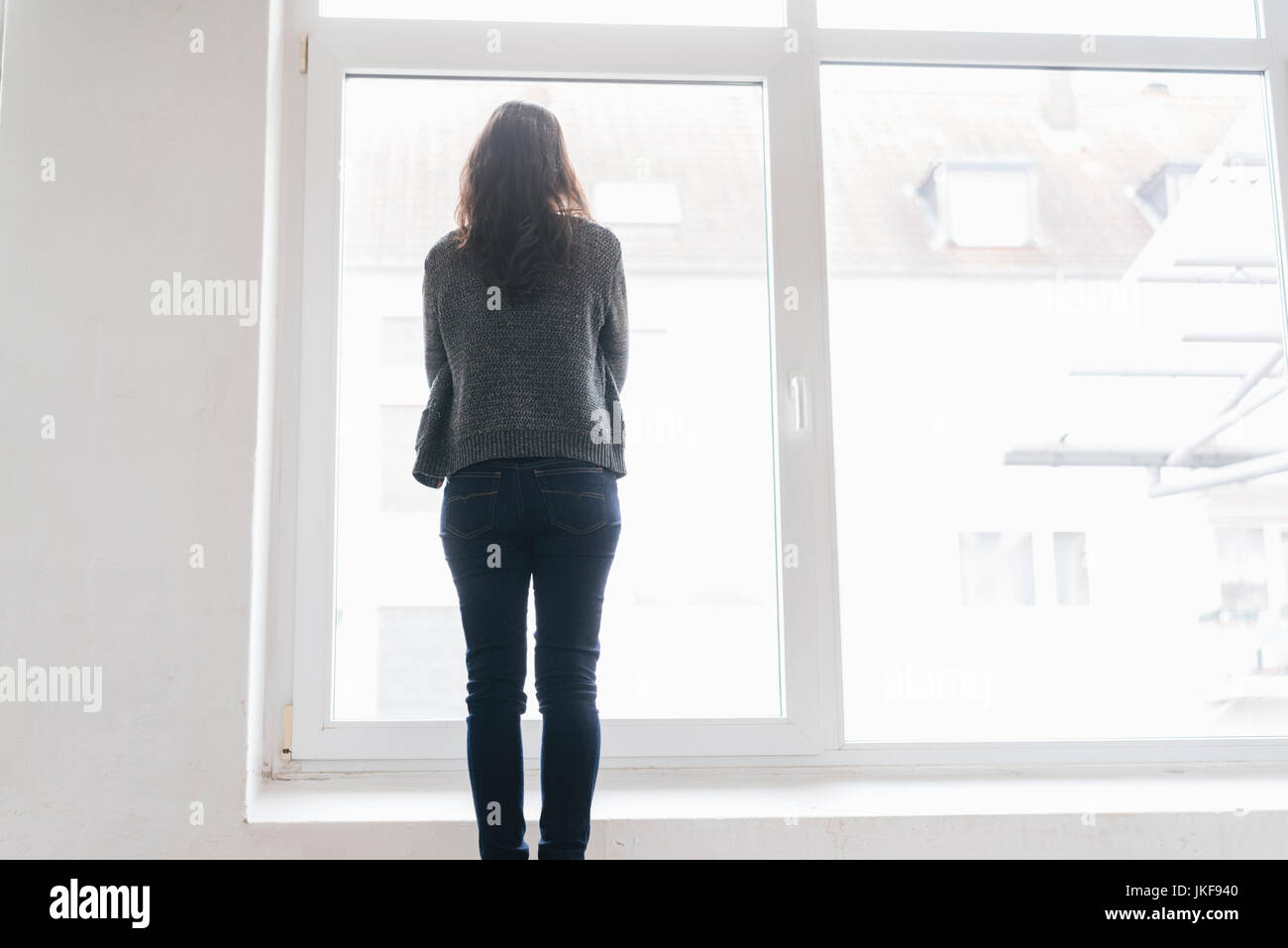 Back view of woman looking through window Stock Photo - Alamy