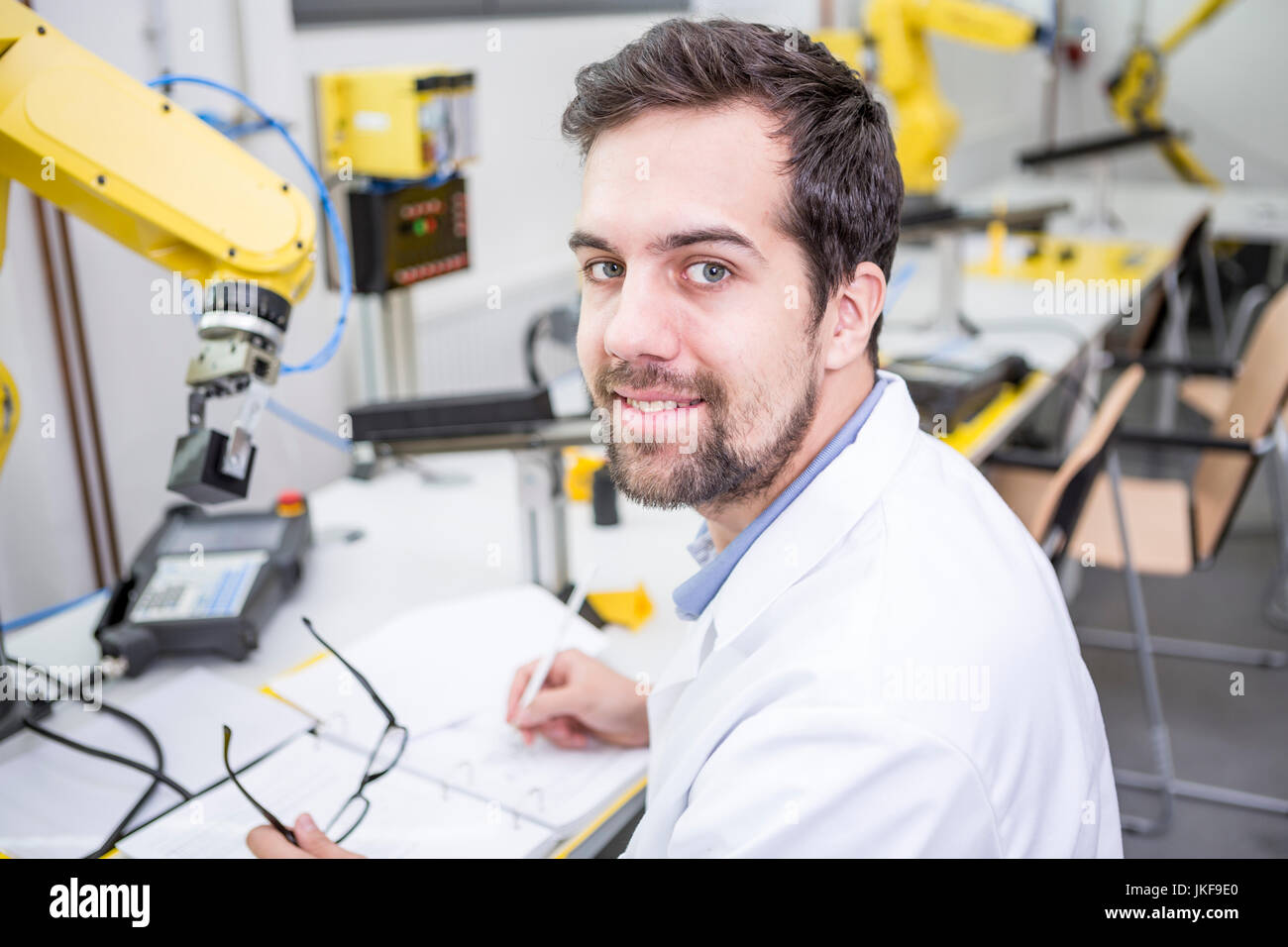 Portrait of smiling engineer in factory taking notes Stock Photo - Alamy