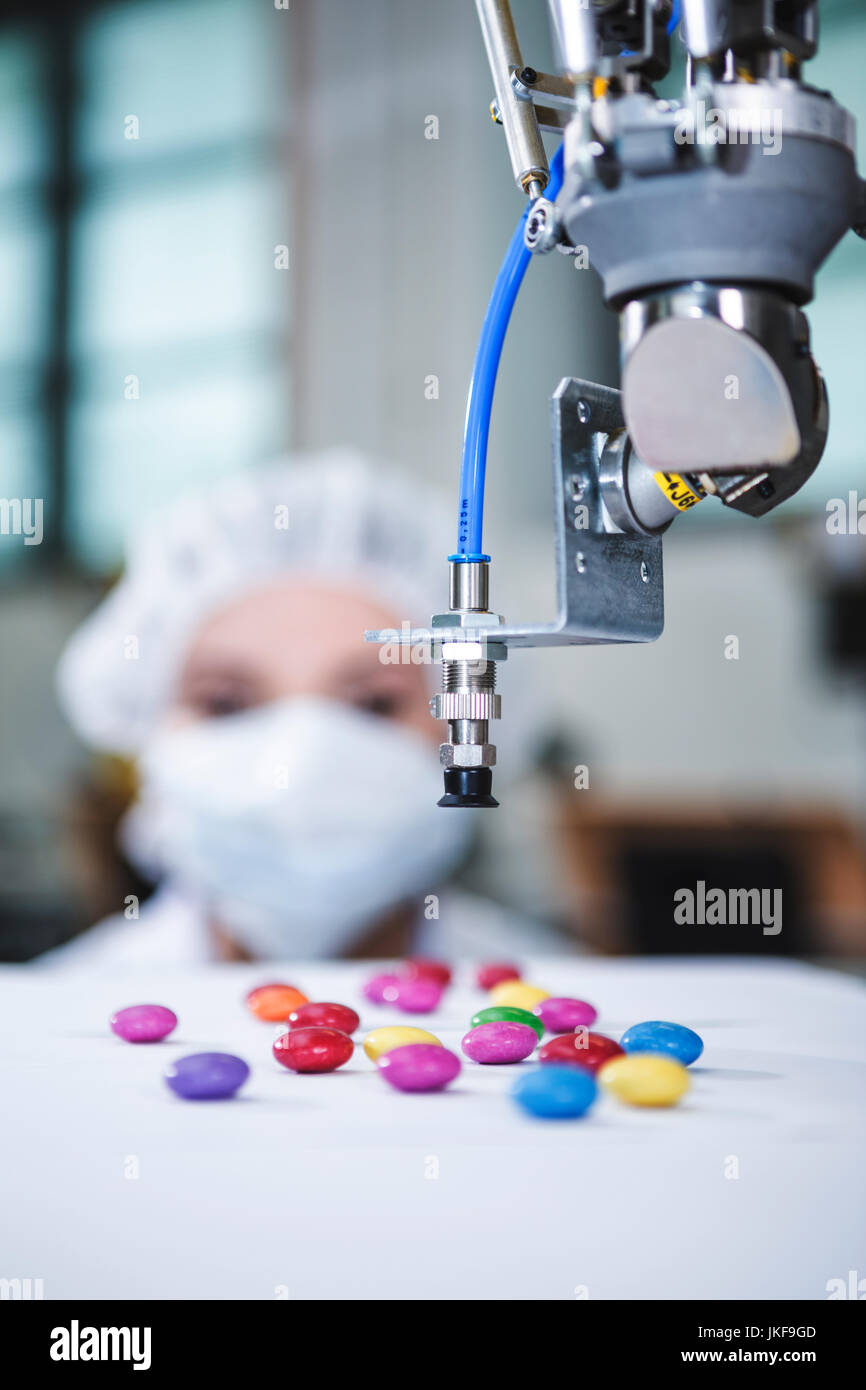 Robot handling sweets with woman in background Stock Photo - Alamy