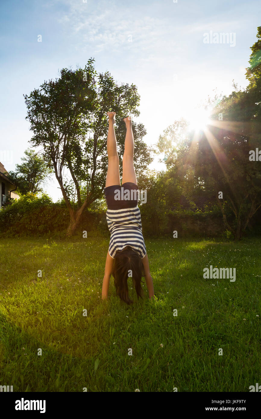 Back view of girl doing handstand on a meadow Stock Photo - Alamy
