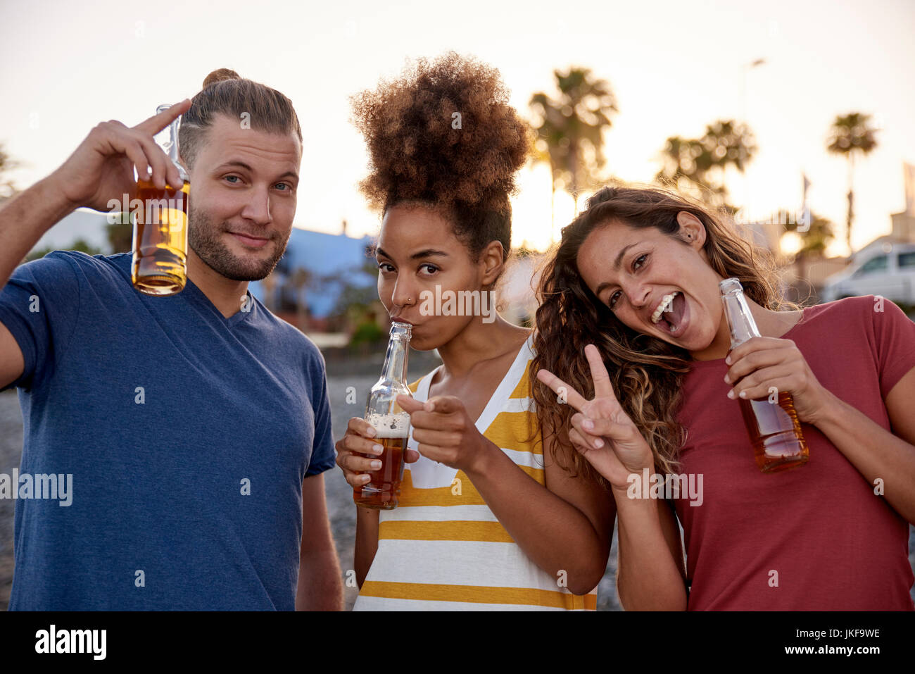 Portrait of three friends with beer bottles having fun on the beach ...