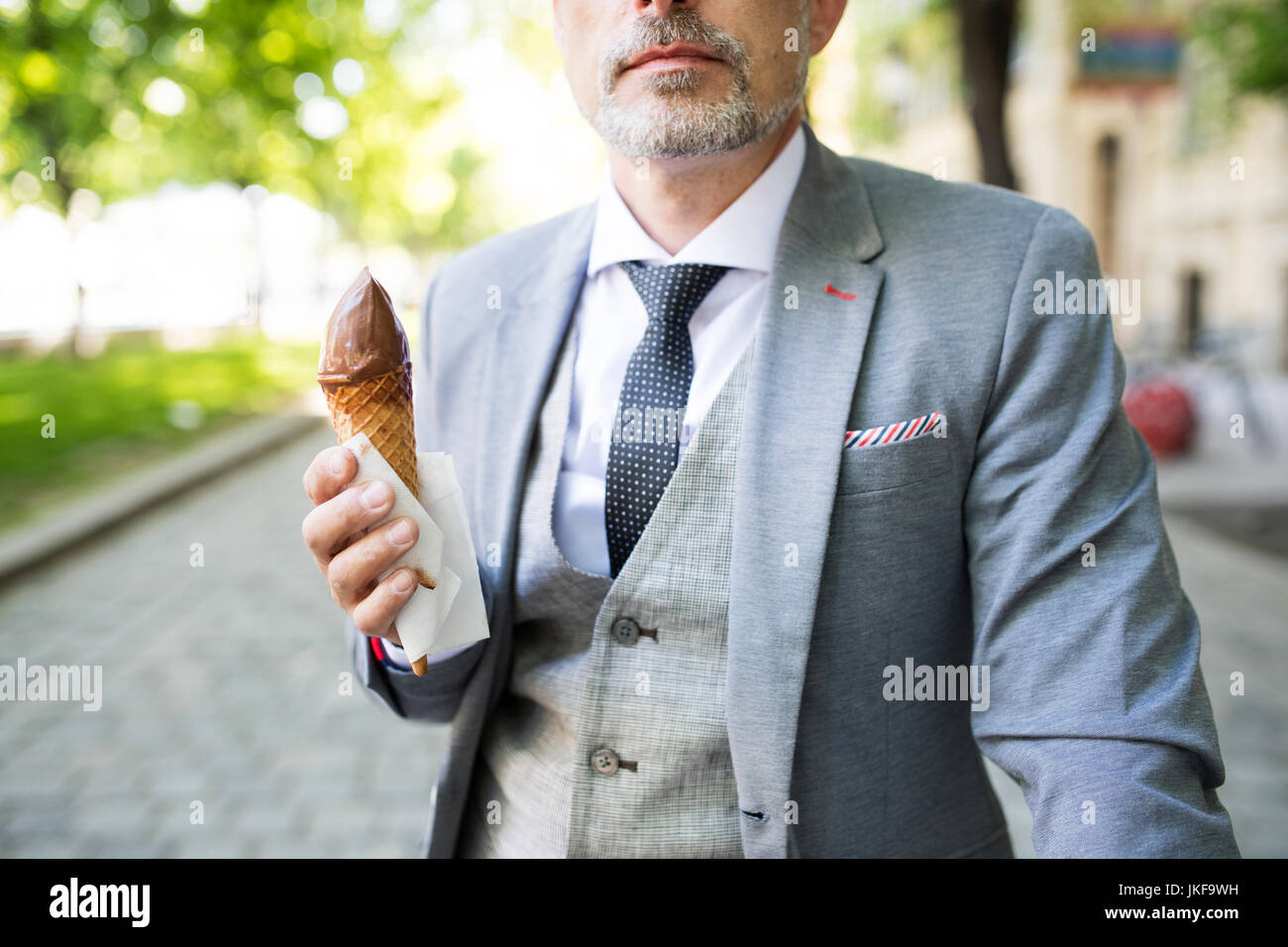 Mature businessman in the city eating ice cream Stock Photo - Alamy