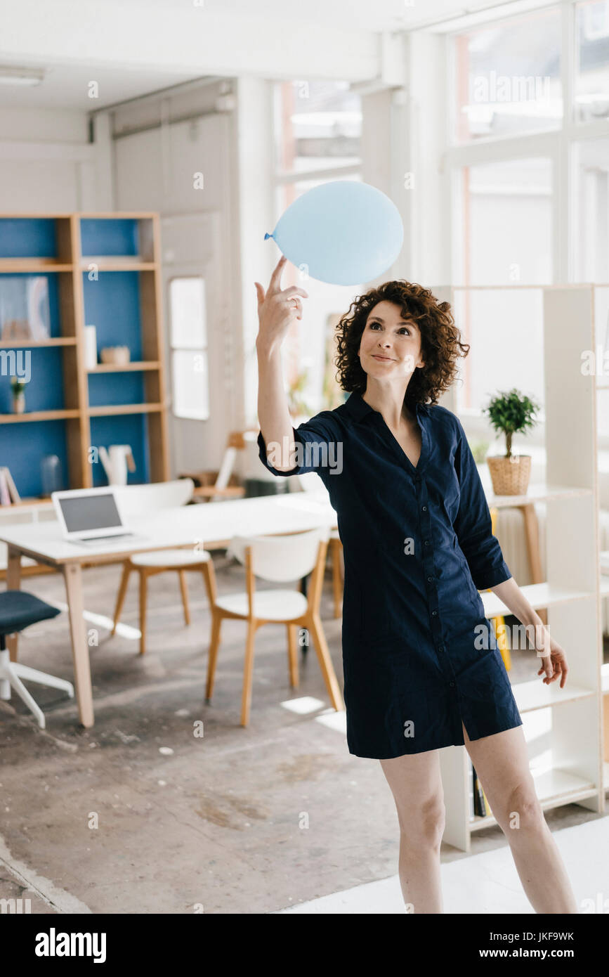 Businesswoman in office balancing balloon on finger Stock Photo - Alamy