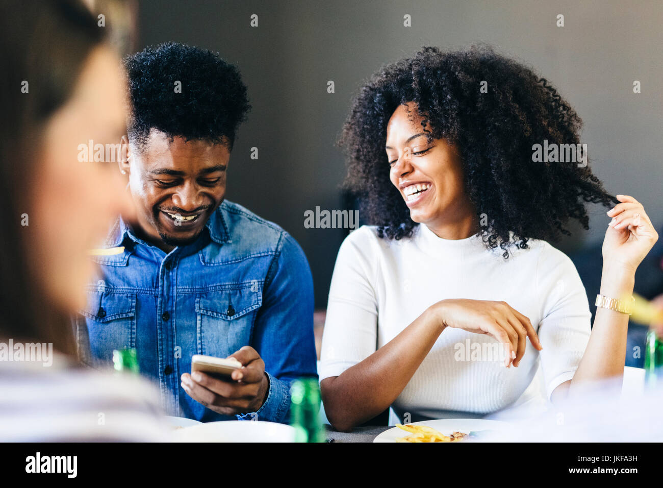 Happy couple sharing cell phone at dining table Stock Photo - Alamy