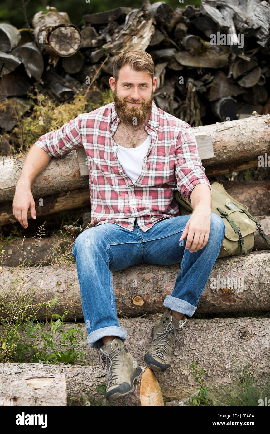 Portrait of bearded man sitting on stack of wood Stock Photo - Alamy