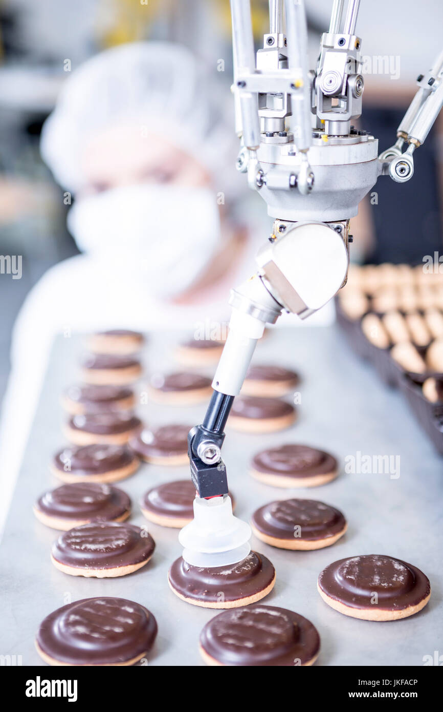 Robot handling cookies with woman in background Stock Photo - Alamy