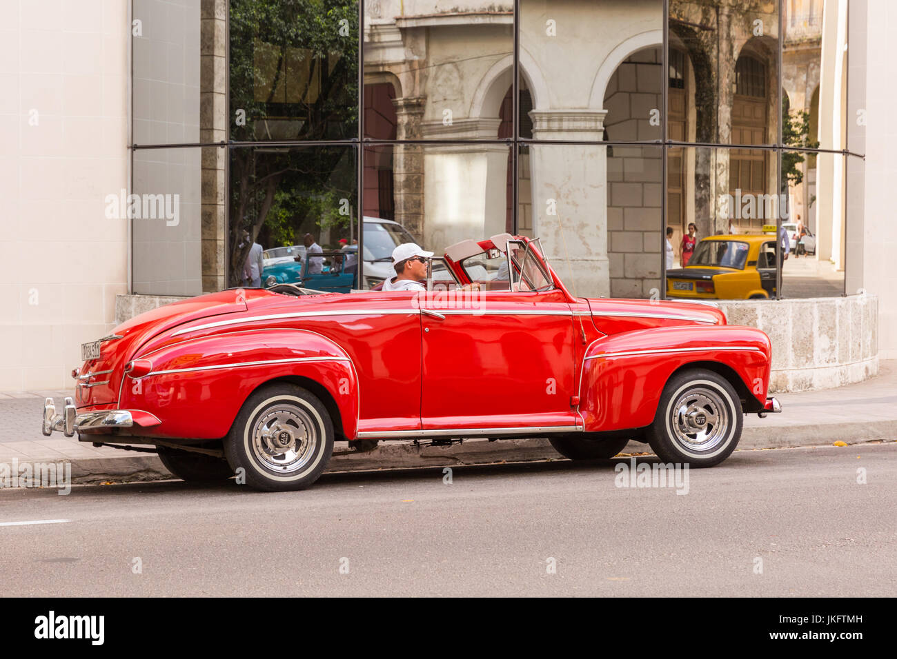 Driver waiting in polished vintage red open top American classic car ...