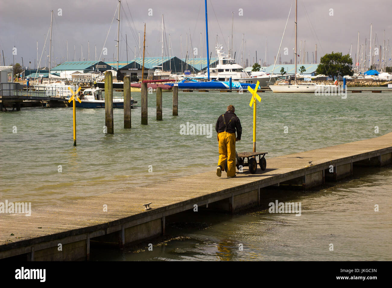 A crew member pushes a buggy along a floating pontoon at the harbour at ...
