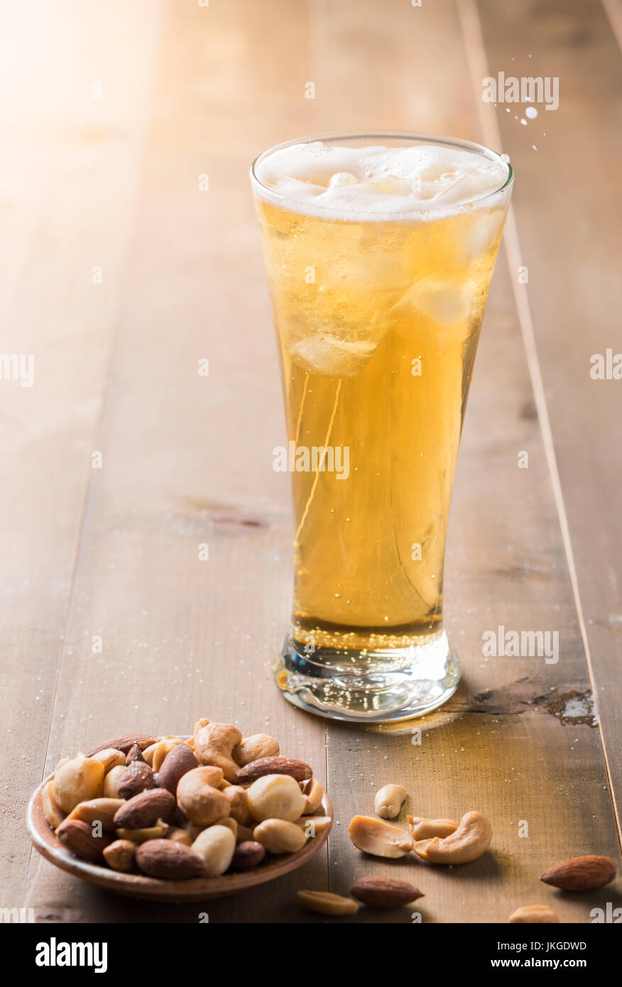 Cold beer with cocktail nut on wood background Stock Photo - Alamy