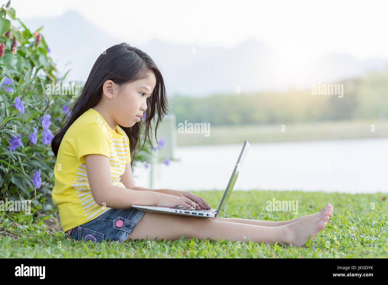 cute girl playing computer on nature background, education cencept ...