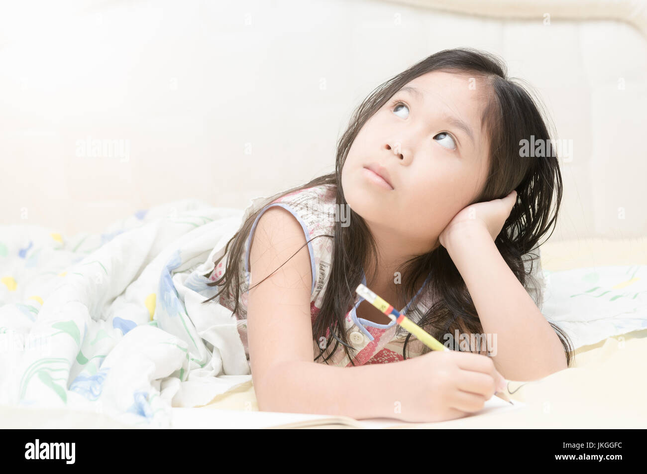cute asian girl thinking and writing to diary on the bed, concept ...