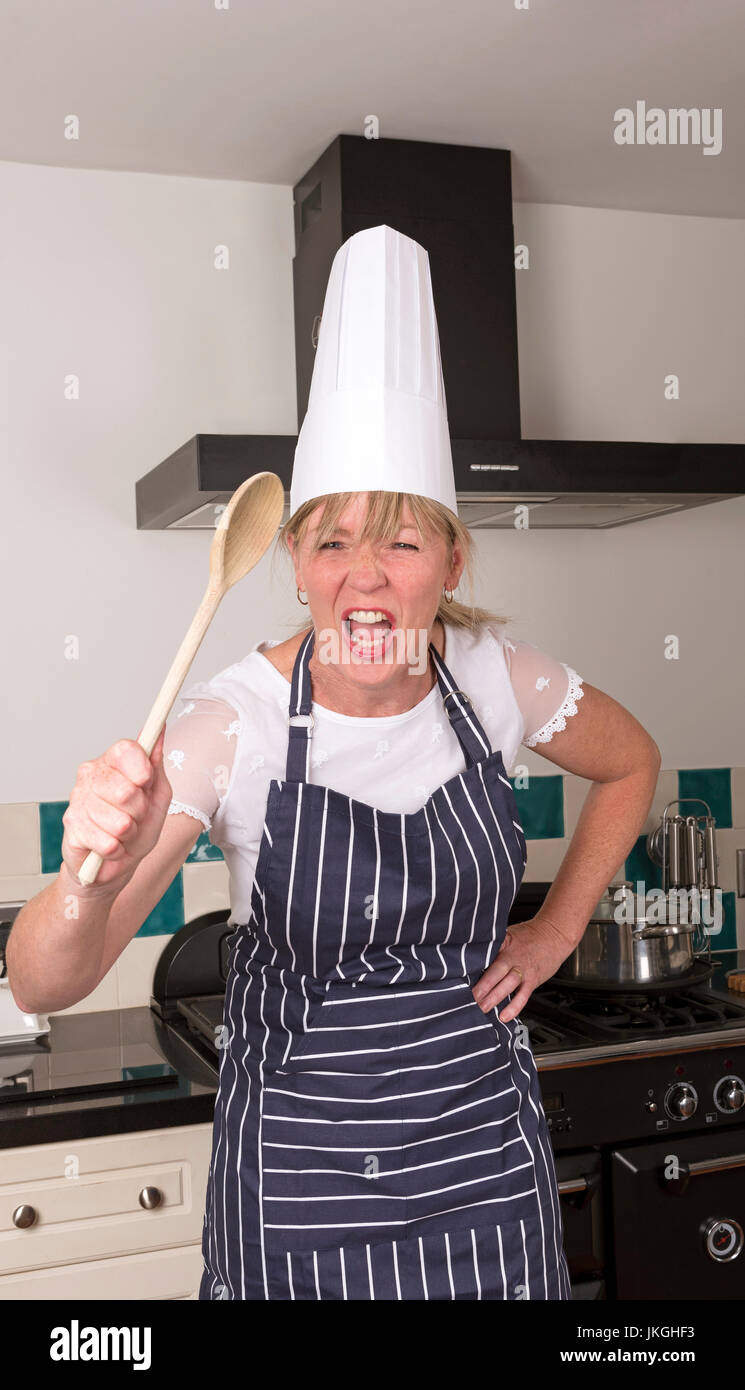Angry woman chef holding a wooden spoon Stock Photo - Alamy
